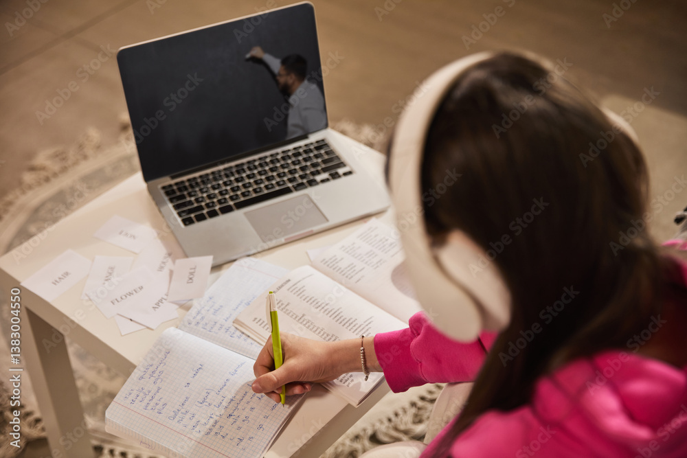 Teen girl in headphones sitting on couch, watching teacher on laptop ...