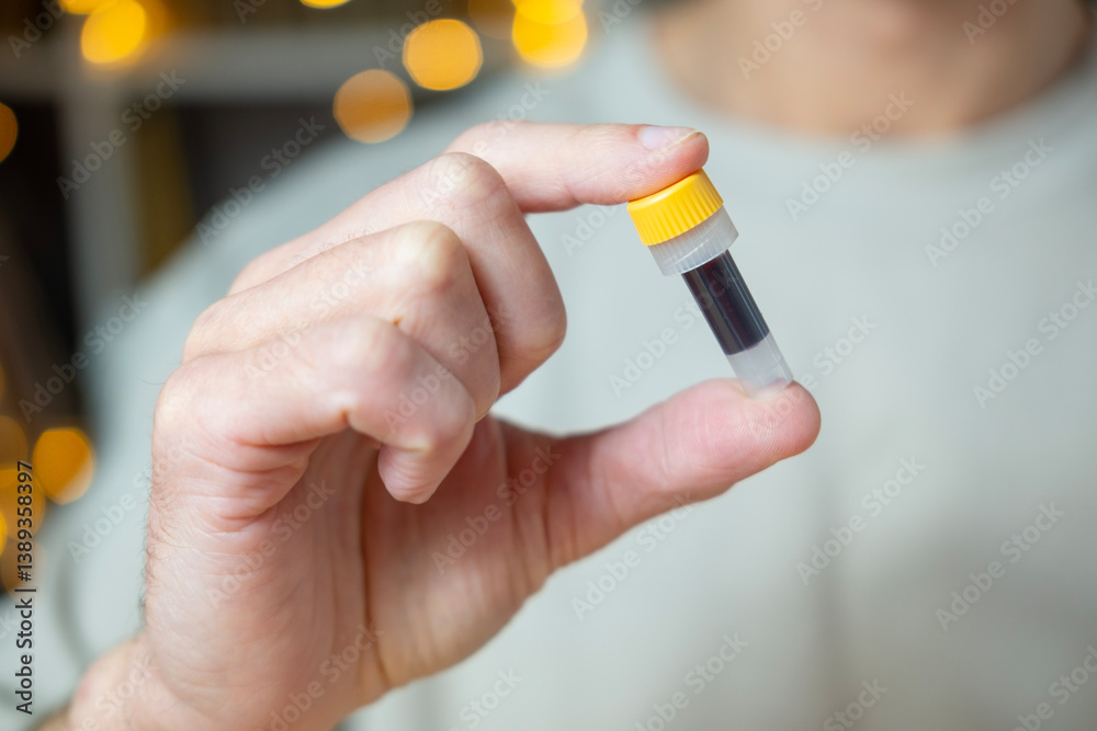 Hands holding blood collection vial and lancet, medical testing and ...