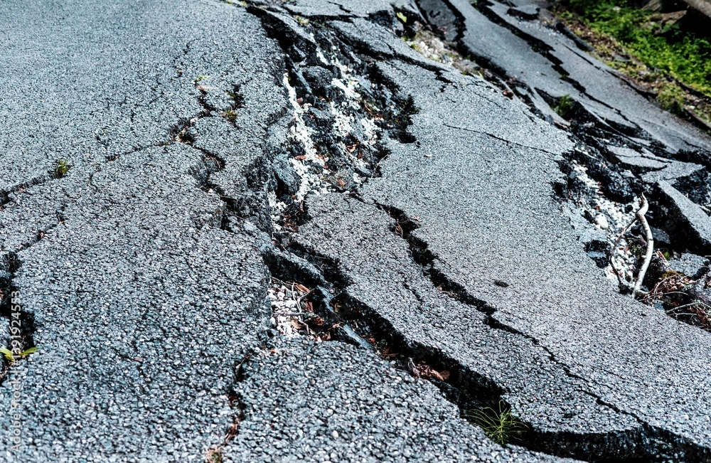 Cracked asphalt surface showing significant damage from seismic ...