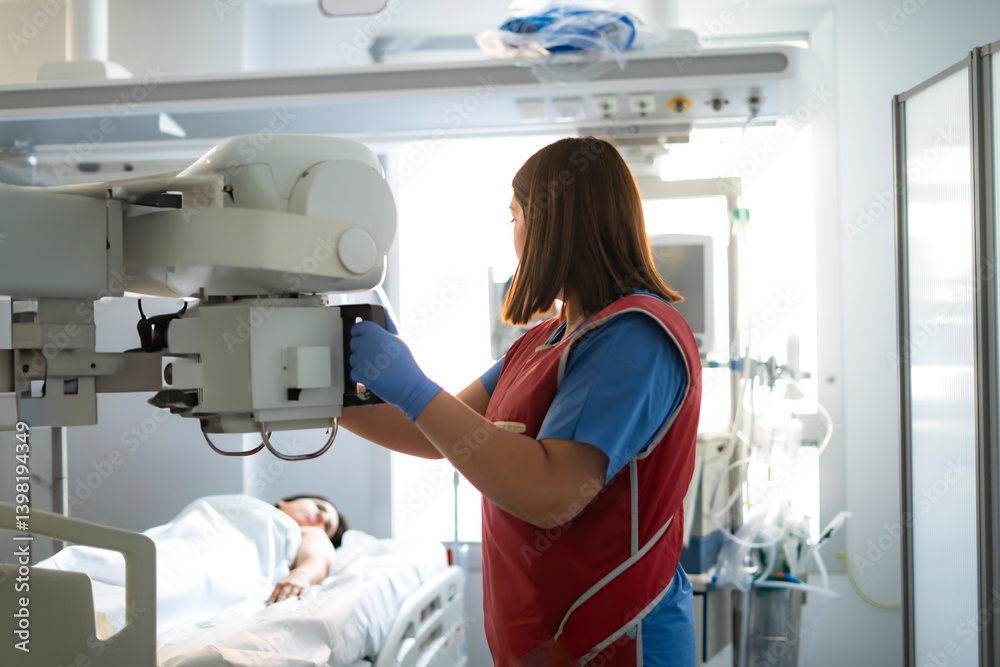 Radiologist positioning x-ray machine over patient lying in hospital ...