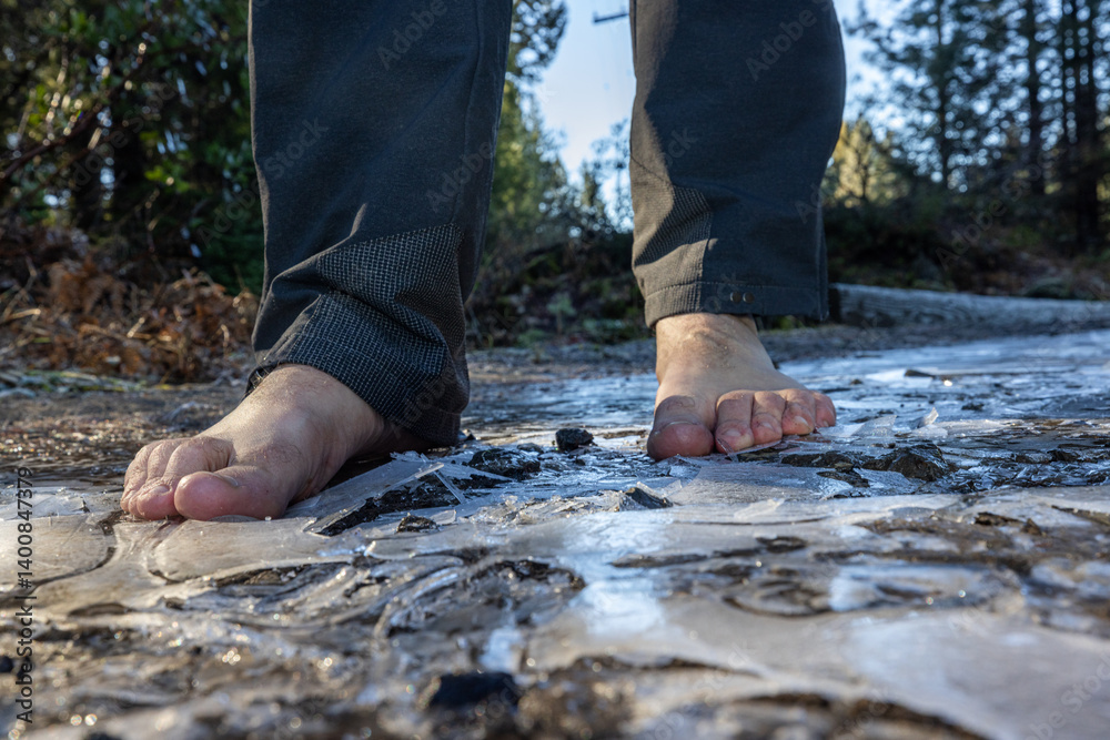 Human feet of an adult male walking barefoot on a frozen puddle as a ...
