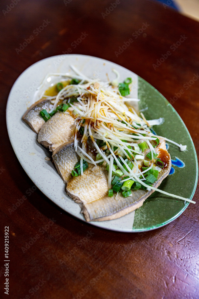 Braised milkfish fillet served cold on a ceramic plate, topped with ...