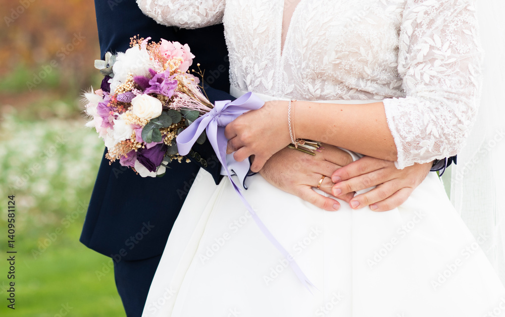 dos novios abrazados juntando sus manos y enseñando el ramo de flores ...