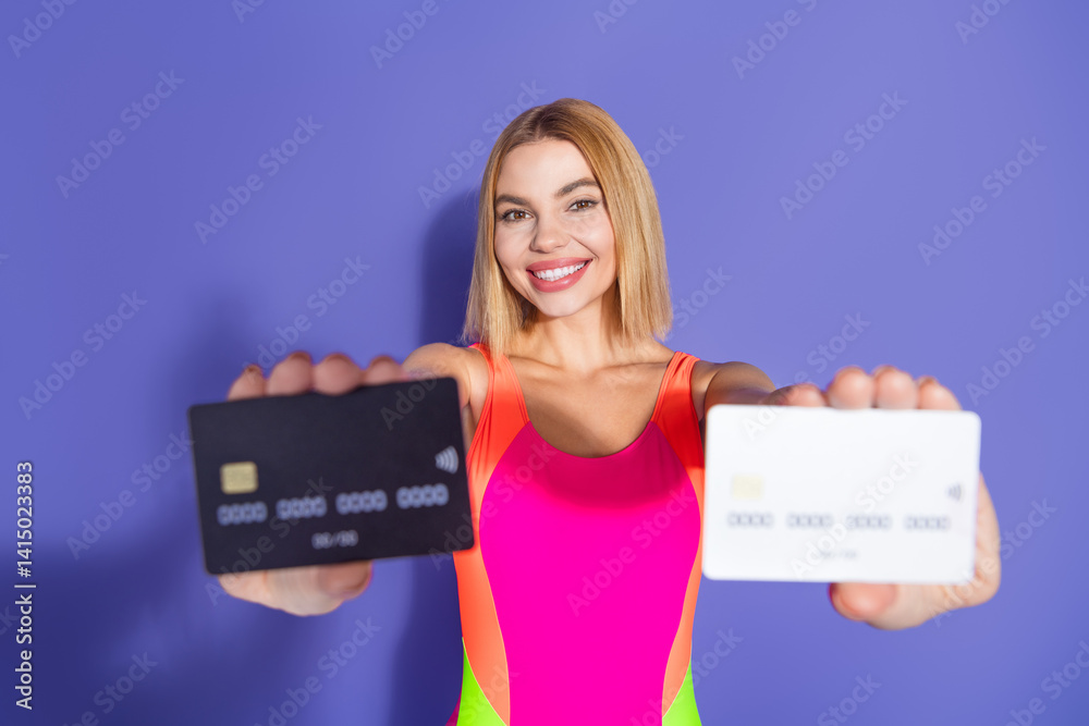 Smiling young woman holding credit cards against purple background ...
