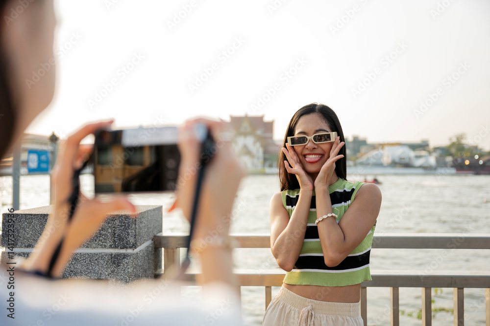 Tourist taking pictures of friend posing by chao phraya river in ...