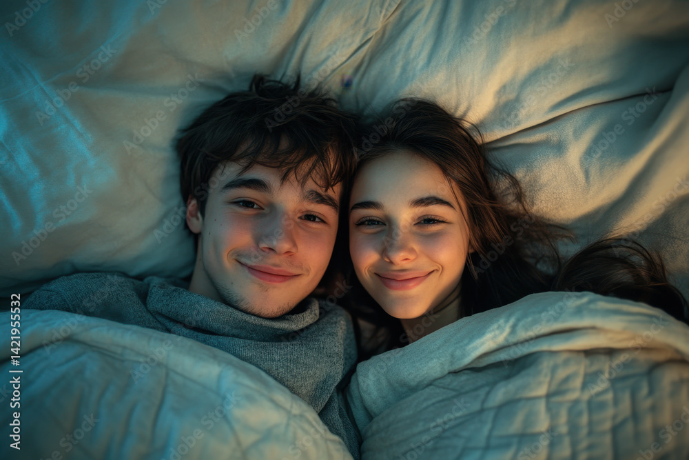Couple cuddling under covers in bed, smiling. Stock Photo | Adobe Stock