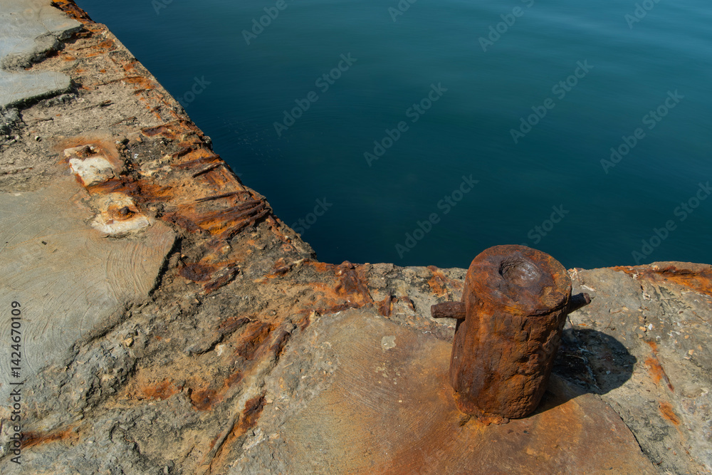 Severely rusted mooring bollard with two horizontal posts fixed to a ...