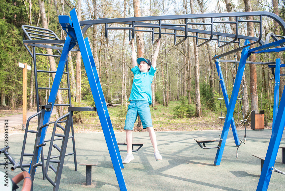 boy hanging by his hands and moving along a horizontal ladder (monkey ...