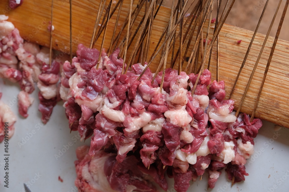 pile of goat satay ready to be grilled. sliced goat meat skewered with ...