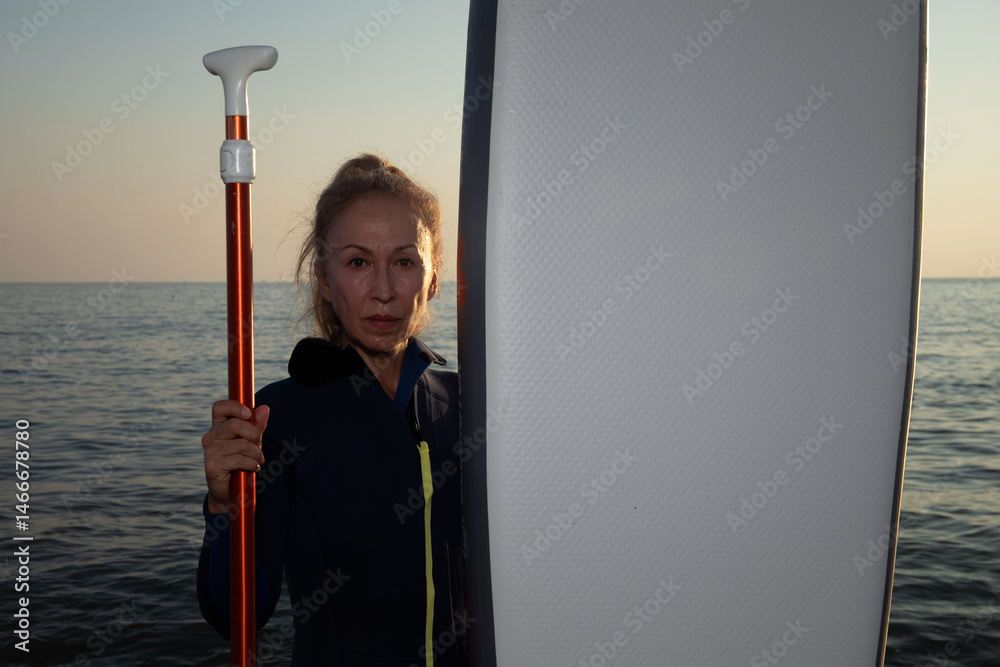 Old oman in wetsuit with surfing board or sup, beach. Senior lady ...