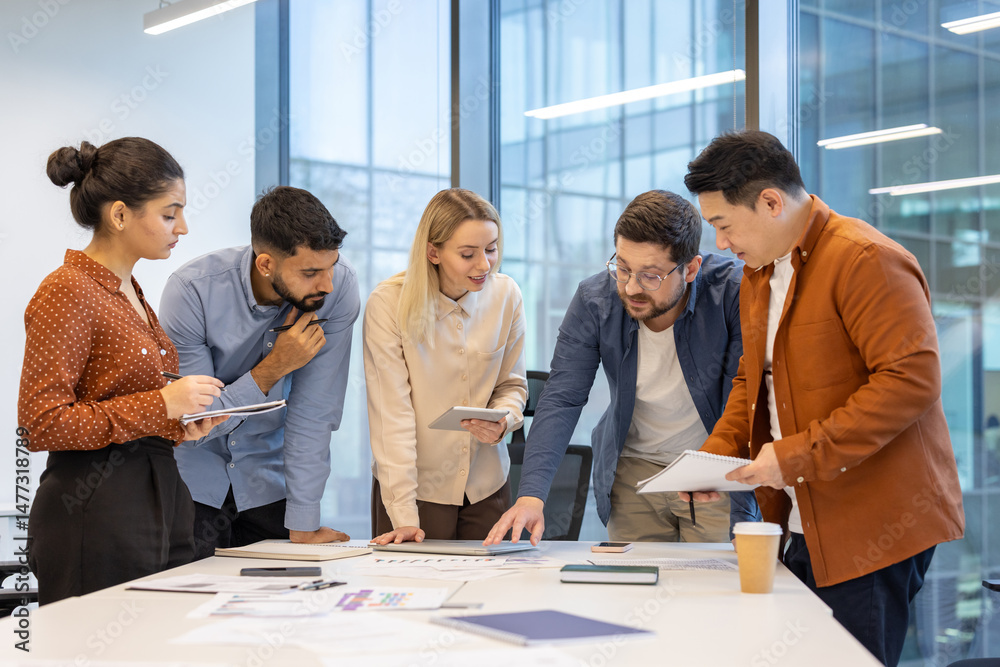 A diverse group of professionals collaborate around a table, reviewing ...