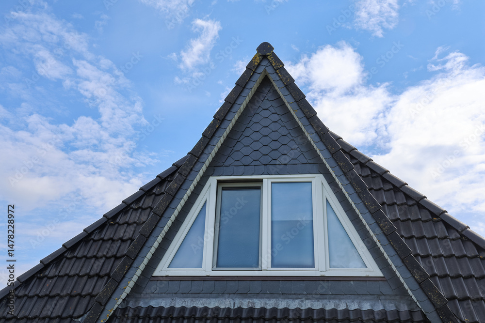 Triangular dormer window with slate cladding and black roof tiles under ...