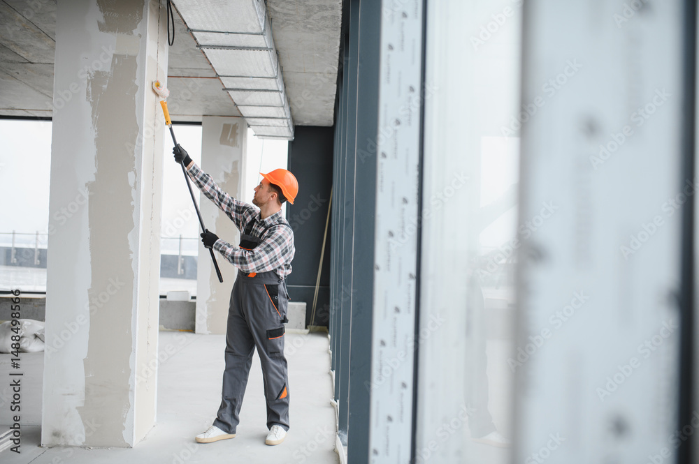 Construction worker painting walls with roller in building renovation ...