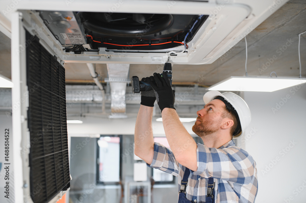 Hvac technician installing air conditioning unit using cordless drill ...
