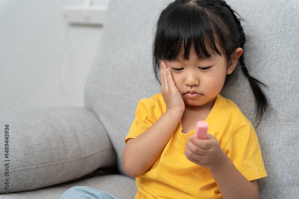 child girl presses hand to cheek after eat sweet, suffers from pain in ...