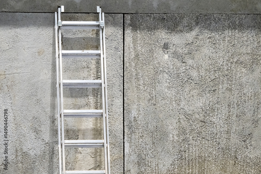 Metal ladder leaning against a rough concrete wall, ready for use in ...