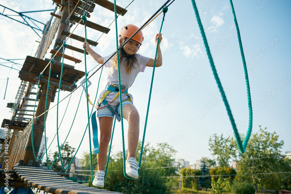Brave little girl child walking rope ladder moving up on obstacle ...