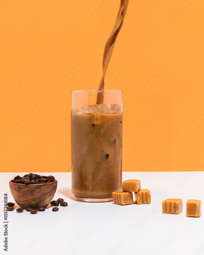 Caramel coffee being poured into glass of ice with coffee and caramels ...
