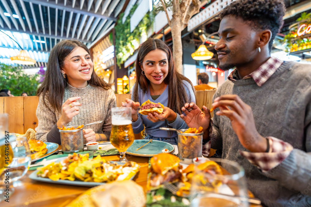 Young friends eating burgers and fries at the restaurant inside a food ...