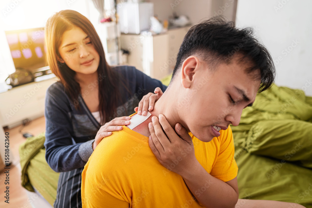 Indonesian southeast asian woman applies a neck pain patch to her ...