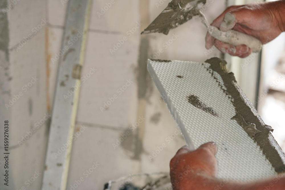 Construction worker applying mortar paste adhesive on insulation foam ...