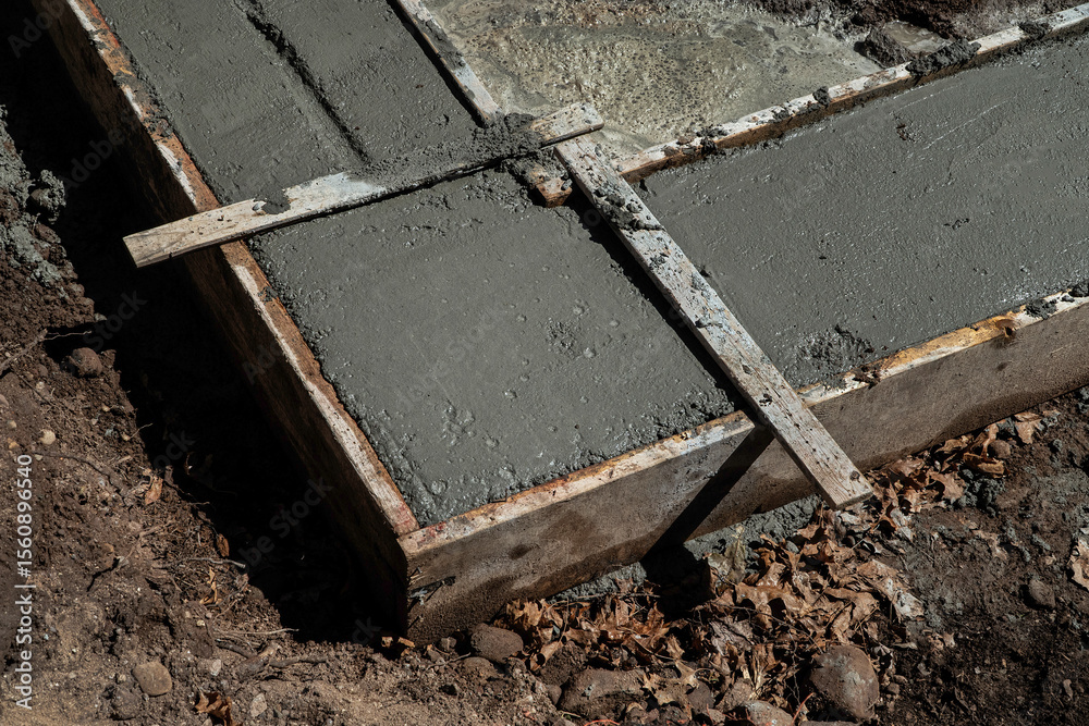 Freshly poured concrete foundation slab within wooden formwork. The ...