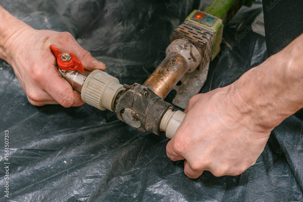 Closeup photo of professional male plumber welding plastic pipe ...