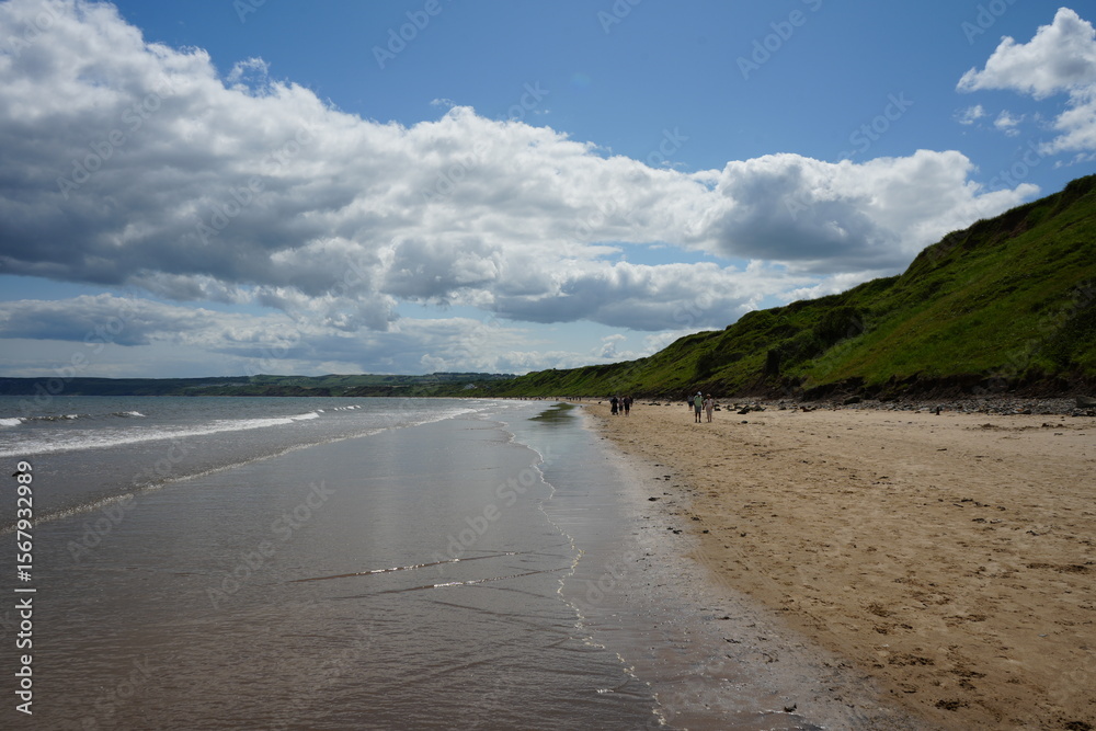 Stunning coastal landscape with sandy beach, rocky cliffs, and walkers ...