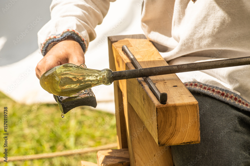 Glassblower or glassworker sculpting a section of the molten glass with ...