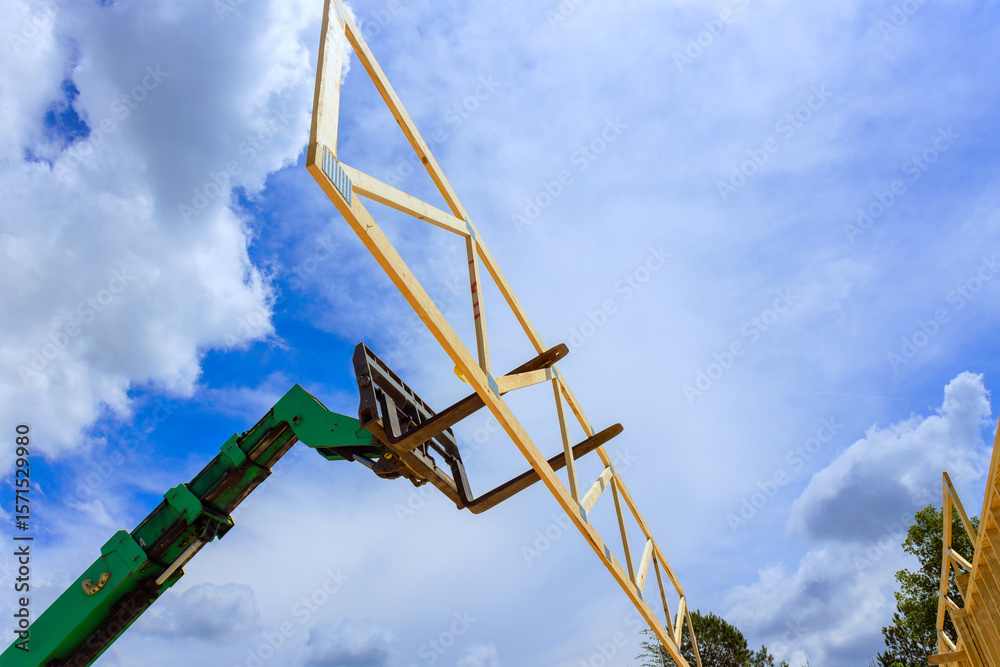 Forklift telehandler machinery raises wooden trusses beams high in air ...