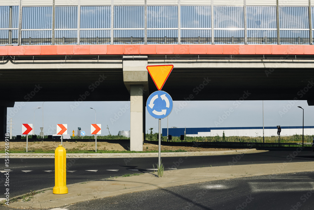 Road sign under modern bridge. Roundabout and yield symbols visible ...