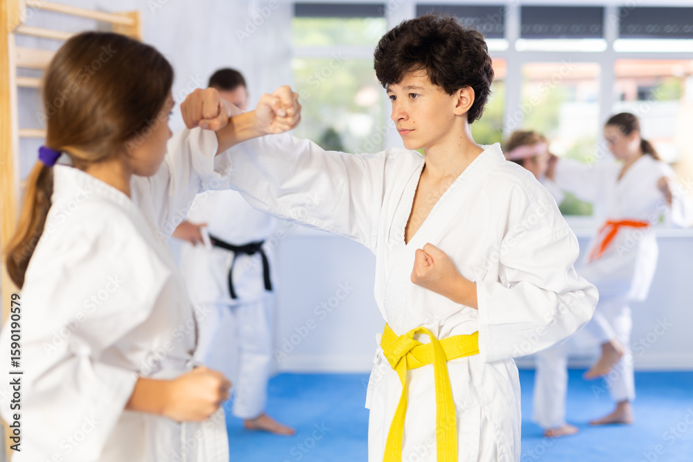 Girl and boy in kimono sparring together in gym during karate training ...