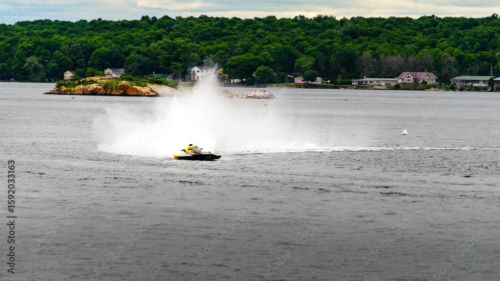 Single yellow and black hydroplane racing boat making a turn, throwing ...
