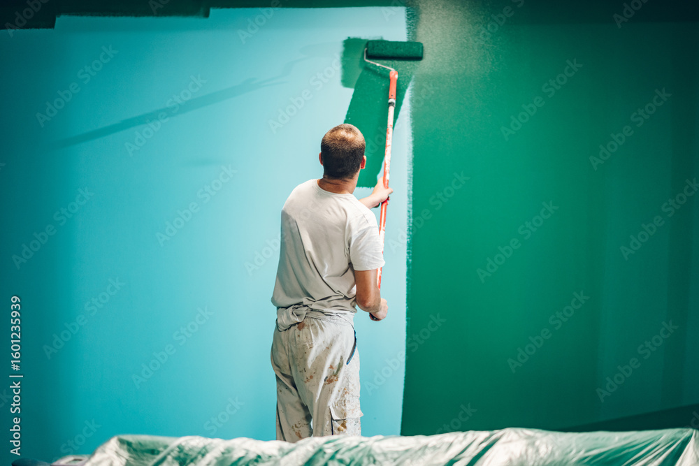 Professional painter applying green paint on wall with roller Stock ...