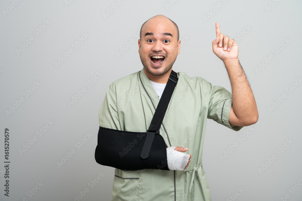 Asian man in patient attire smiles gently at the camera, wearing an arm ...