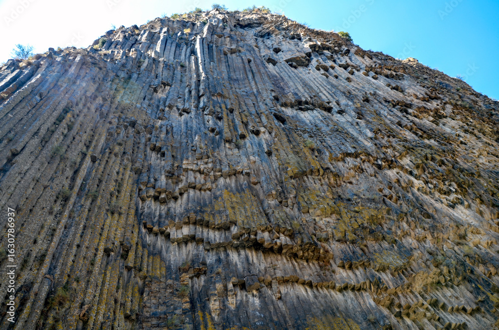 Low angle shot showcases a towering cliff face composed of tightly ...