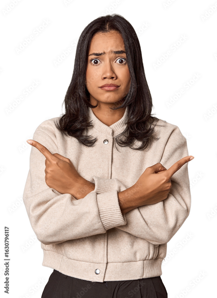 Young filipino woman points sideways, is trying to choose between two options. Stock Photo ...