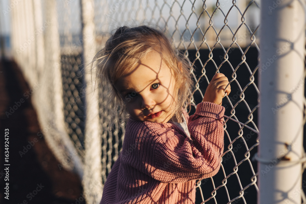 Toddler girl in sweater with chain-link fence shadows Stock Photo ...