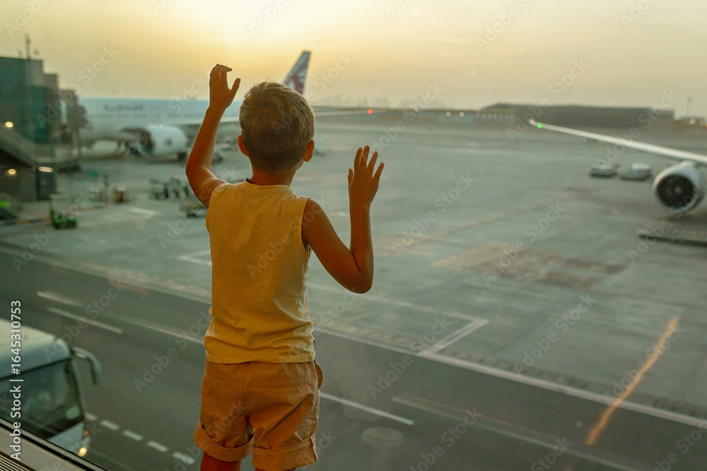 Child, watching from the window of the airport the planes, taking off ...
