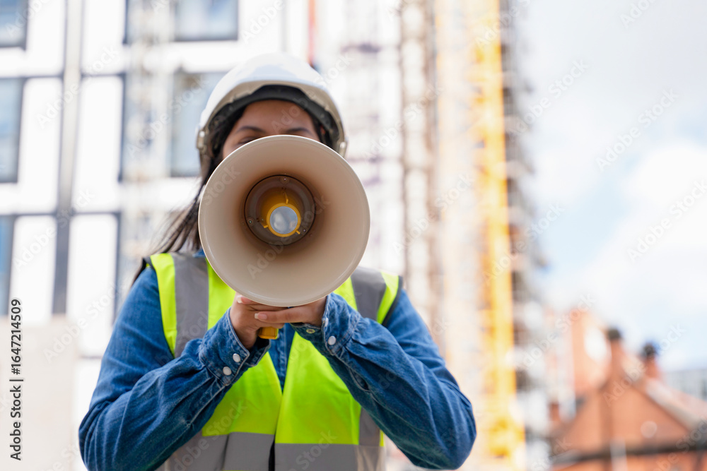 Portrait of young woman construction worker in bright safety jacket ...