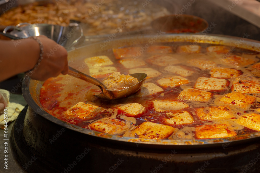 Steaming ladle lifting soft Taiwanese braised tofu from chili-infused ...