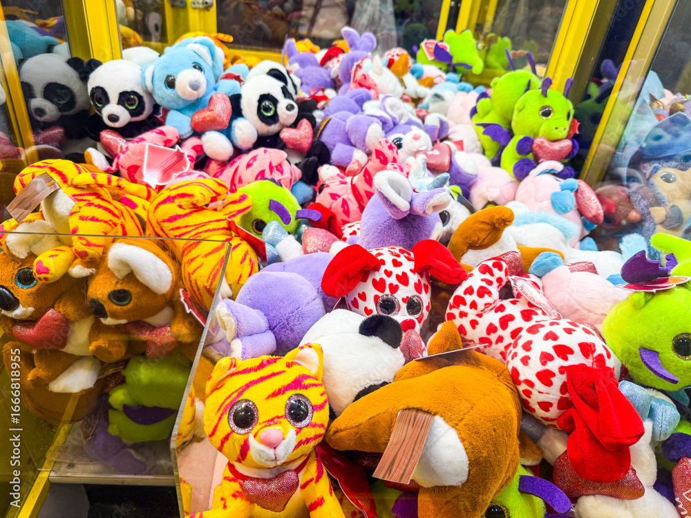 Claw machine filled with colorful stuffed animals and toys ...