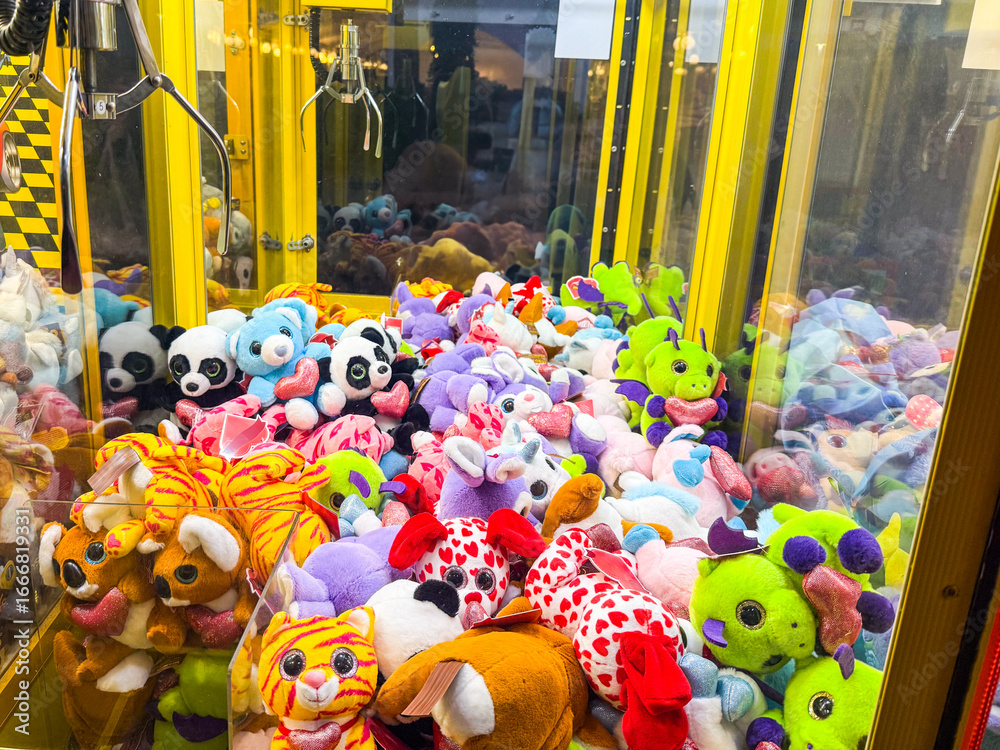 Claw machine filled with colorful stuffed animals and toys ...