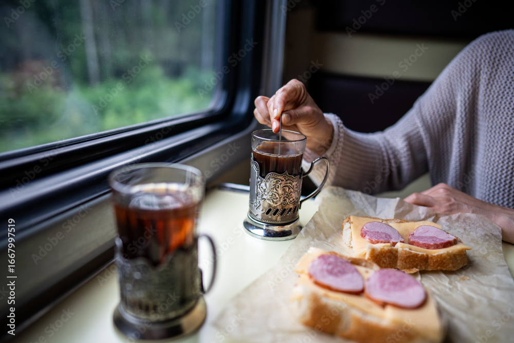 Passenger on train eating sandwich, drinking tea while look out window ...