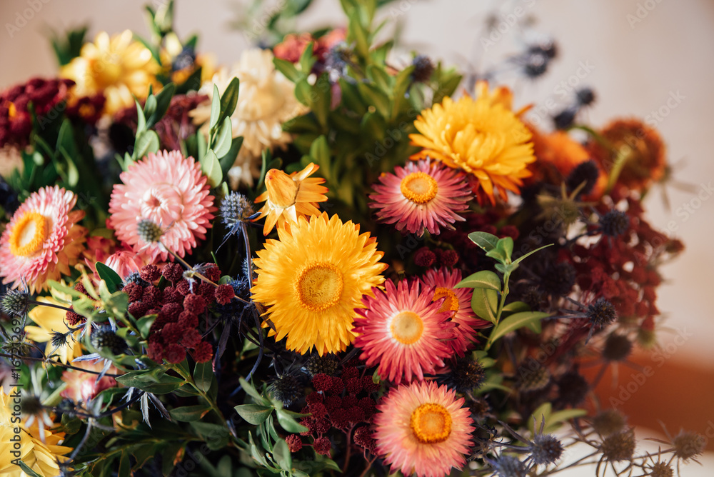 Autumn bouquet with vibrant strawflowers and mixed foliage in warm ...