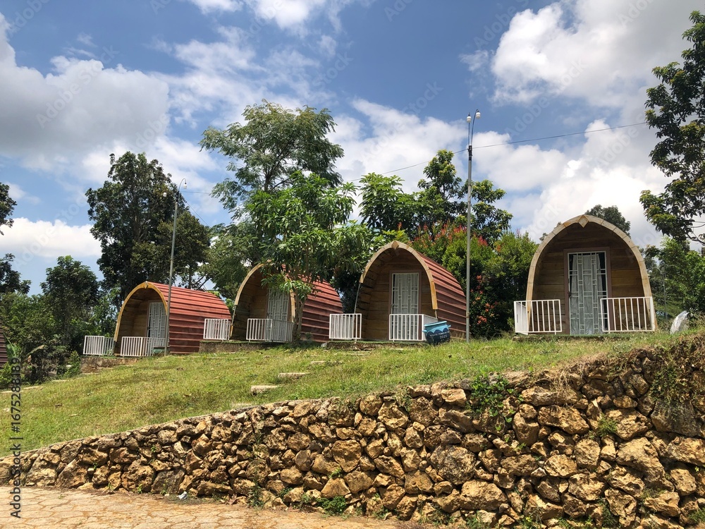 Glamping pods on a scenic hillside under a bright sky, offering a ...