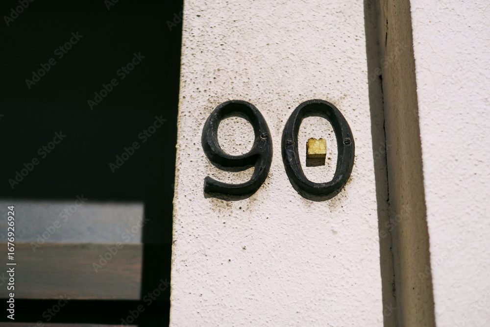 Numéro 90. Plaque de numéro de rue. Chiffres noirs sur pilier blanc ...