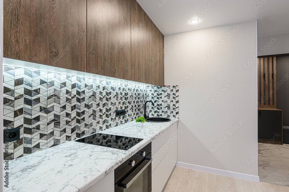 Modern kitchen features wood cabinets, chevron tile backsplash, marble ...