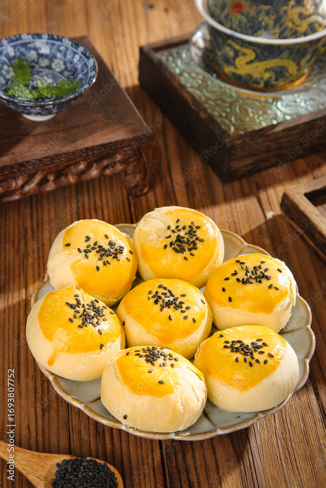 Asian egg yolk pastries with sesame seeds and traditional tea service ...