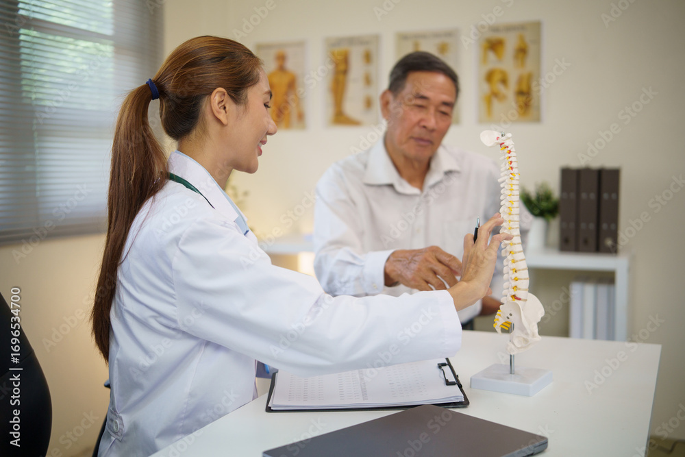Female doctor explains spinal structure to senior male patient using a ...